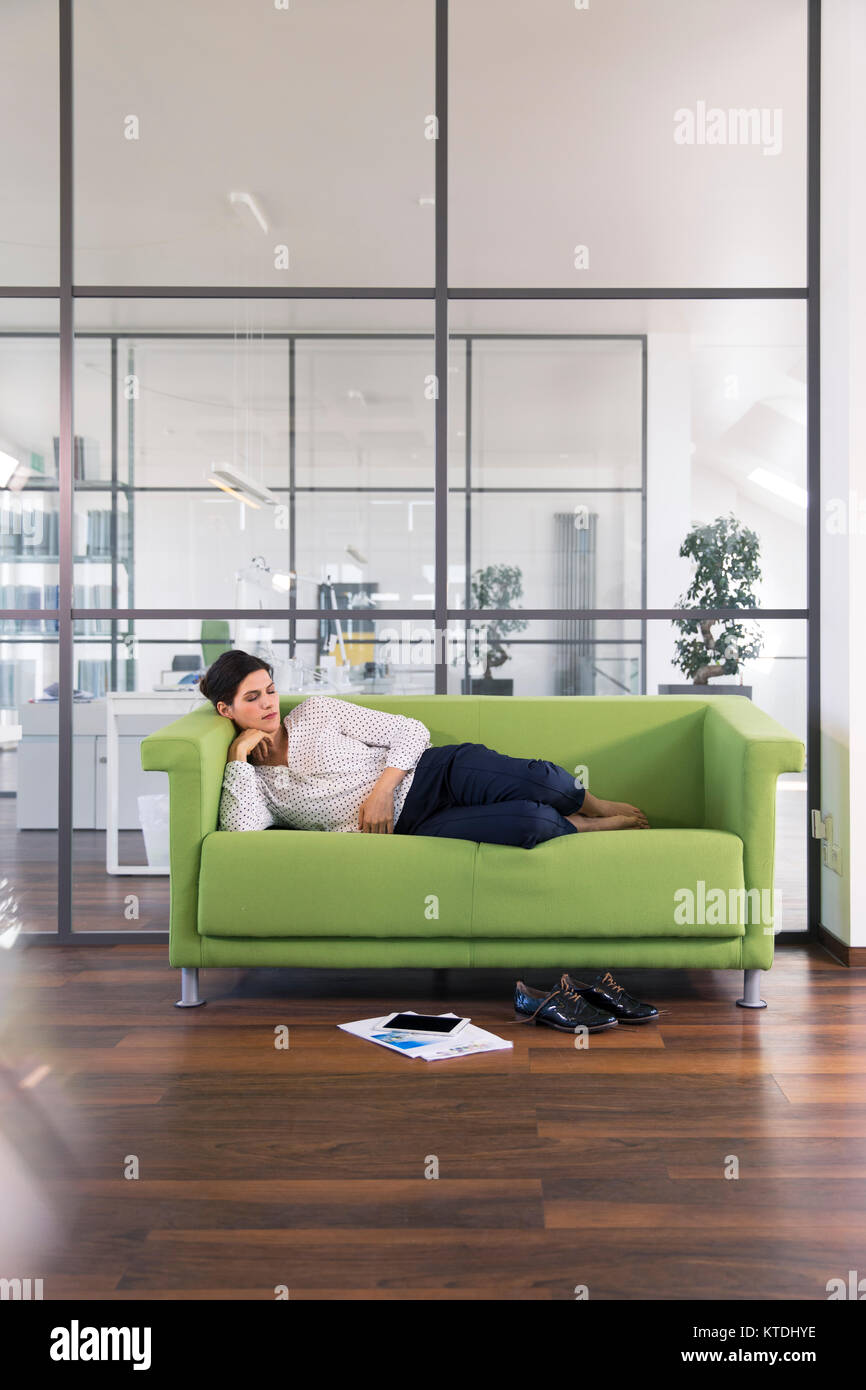 Businesswoman taking a nap lying on a couch in the office Stock Photo ...