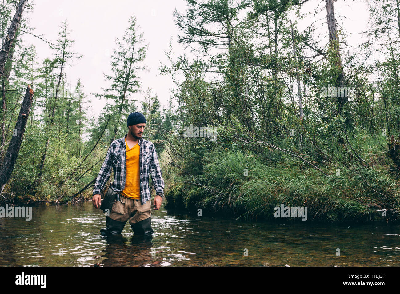 Man standing in river with waders Stock Photo - Alamy