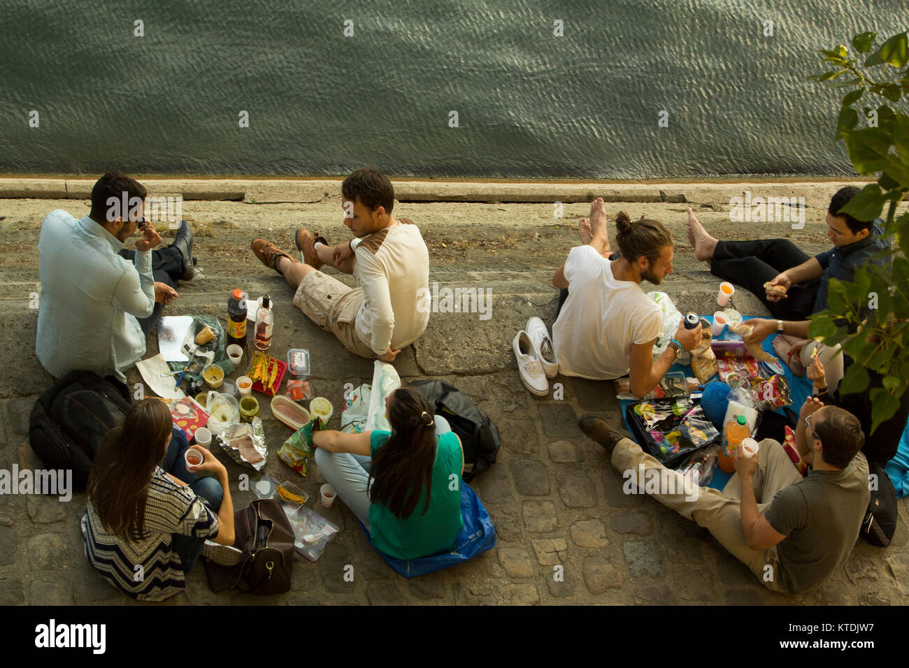 Many young people relaxing at summer afternoon in île Saint-Louis on the banks of river Seine in ...