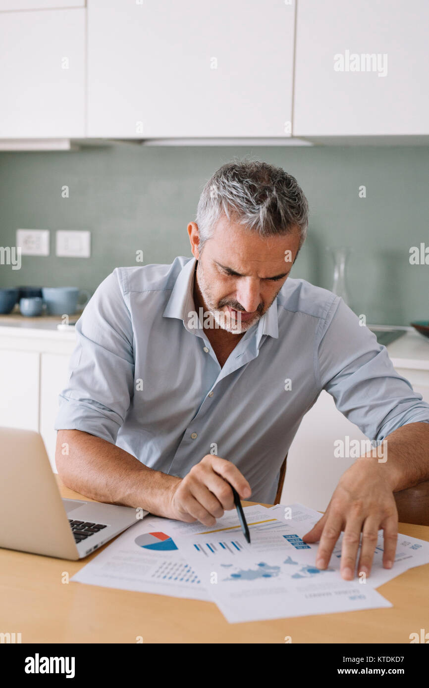 Man analysing data and using laptop in home office Stock Photo - Alamy