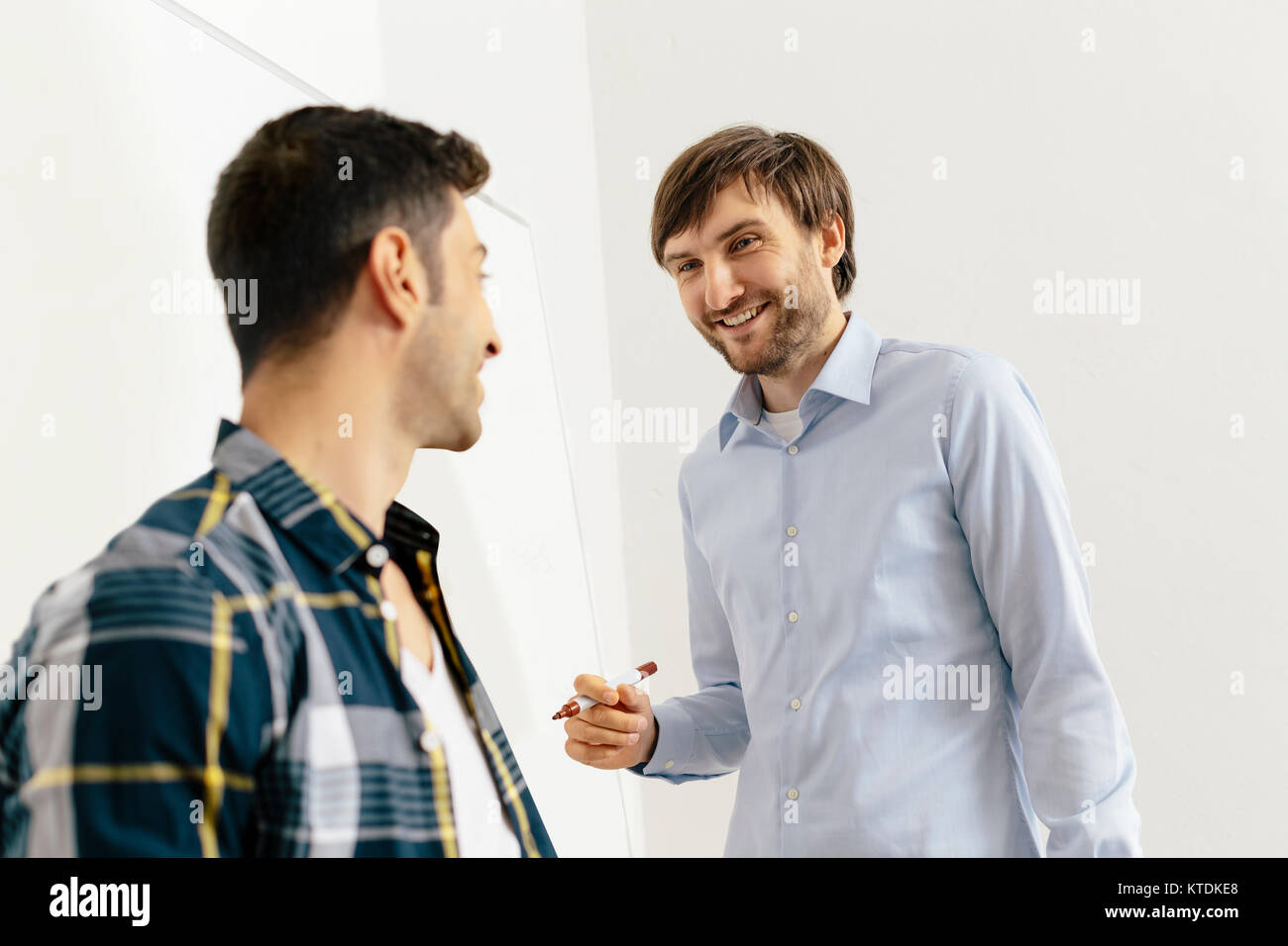 Two smiling colleagues at whiteboard in office Stock Photo - Alamy