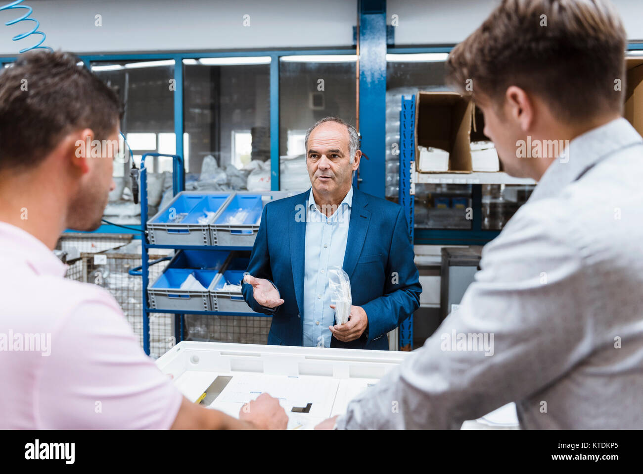 Business people standing on shop floor, discussing product improvement ...