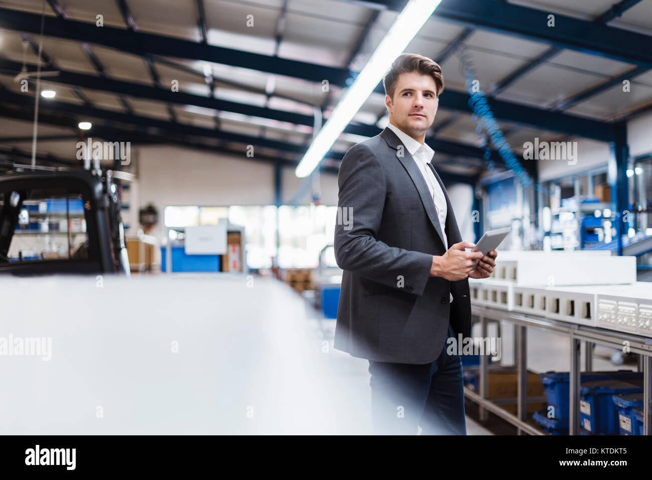 Young manager standing in shop floor with digital tablet, portrait ...
