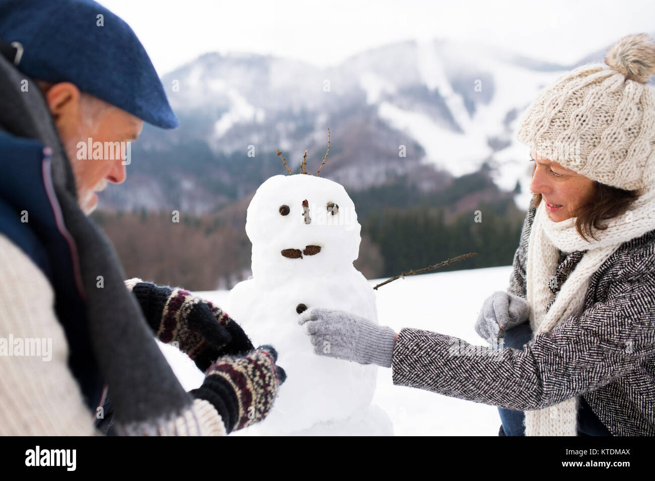 Senior couple building up snowman in winter landscape Stock Photo - Alamy