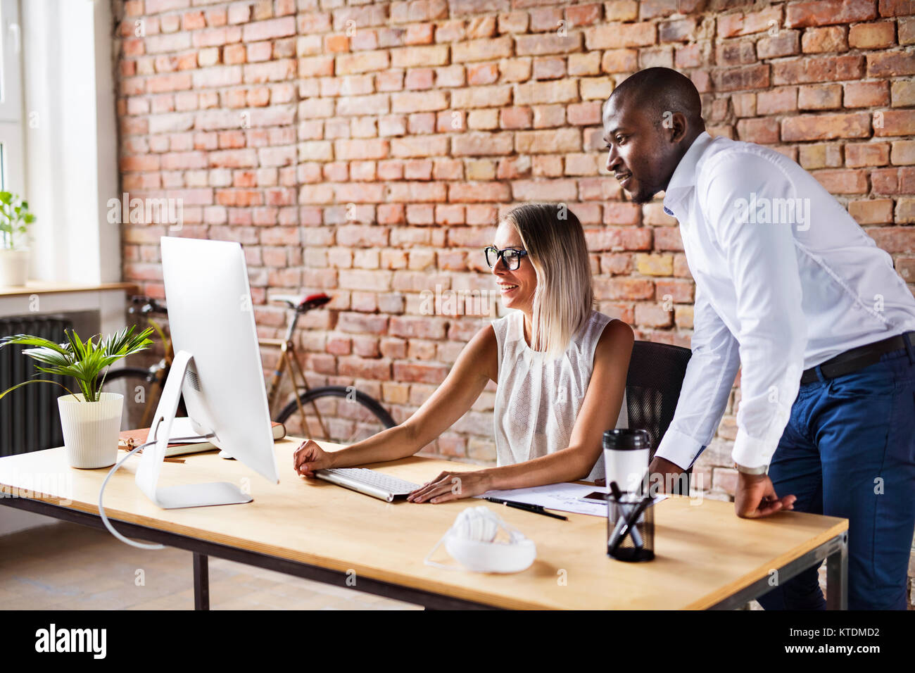 Two colleagues working together at desk in office Stock Photo - Alamy