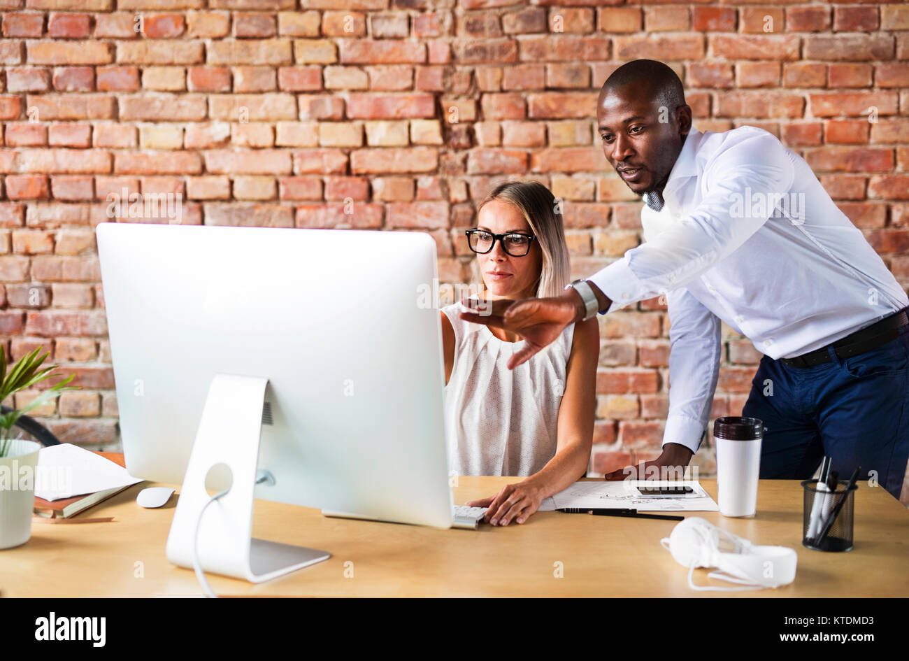 Two colleagues working together at desk in office Stock Photo - Alamy