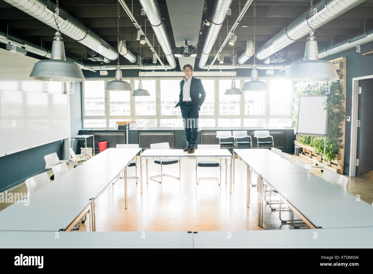 Businessman standing on table in conference room Stock Photo - Alamy