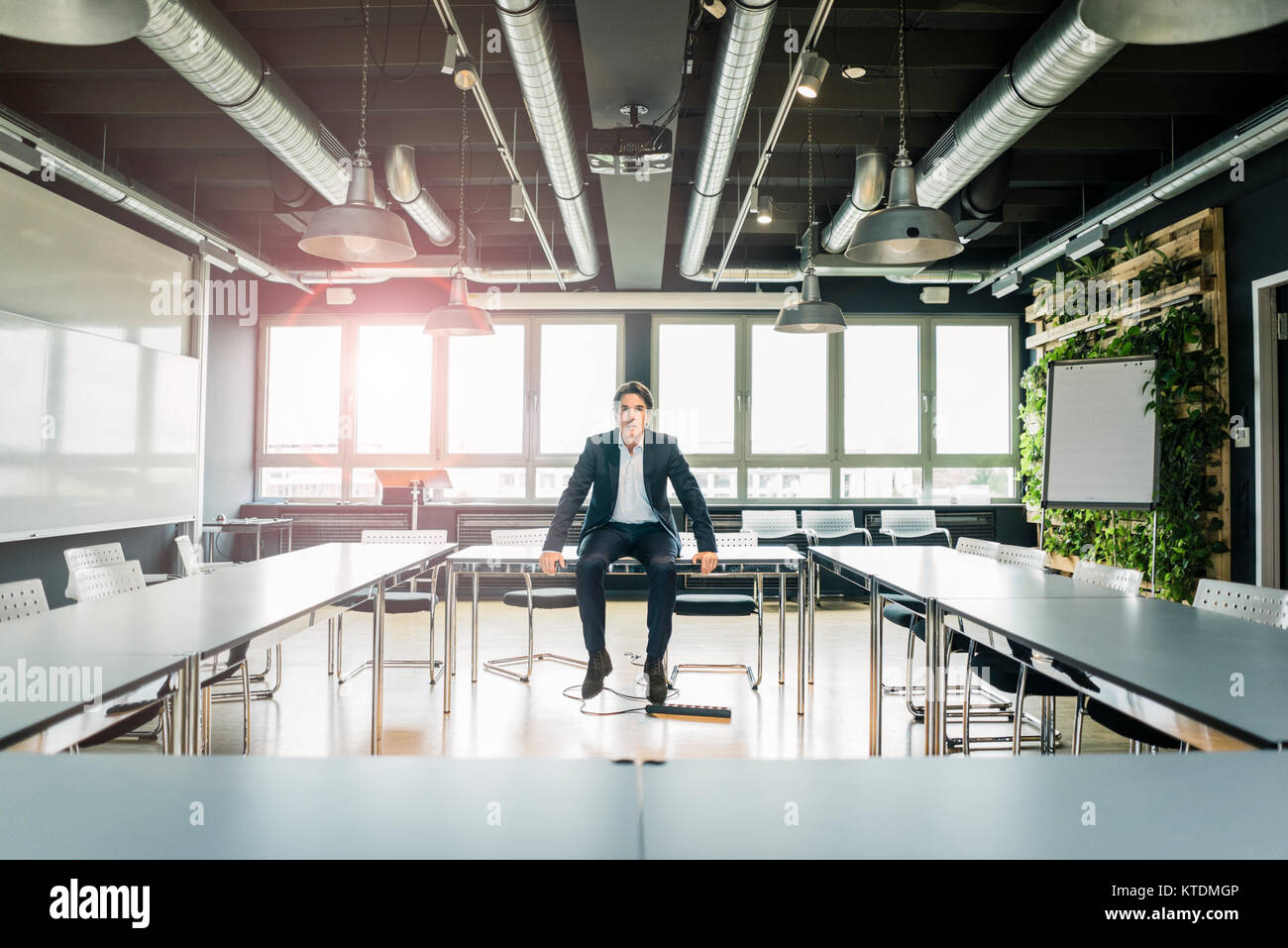 Businessman sitting on table in conference room Stock Photo - Alamy