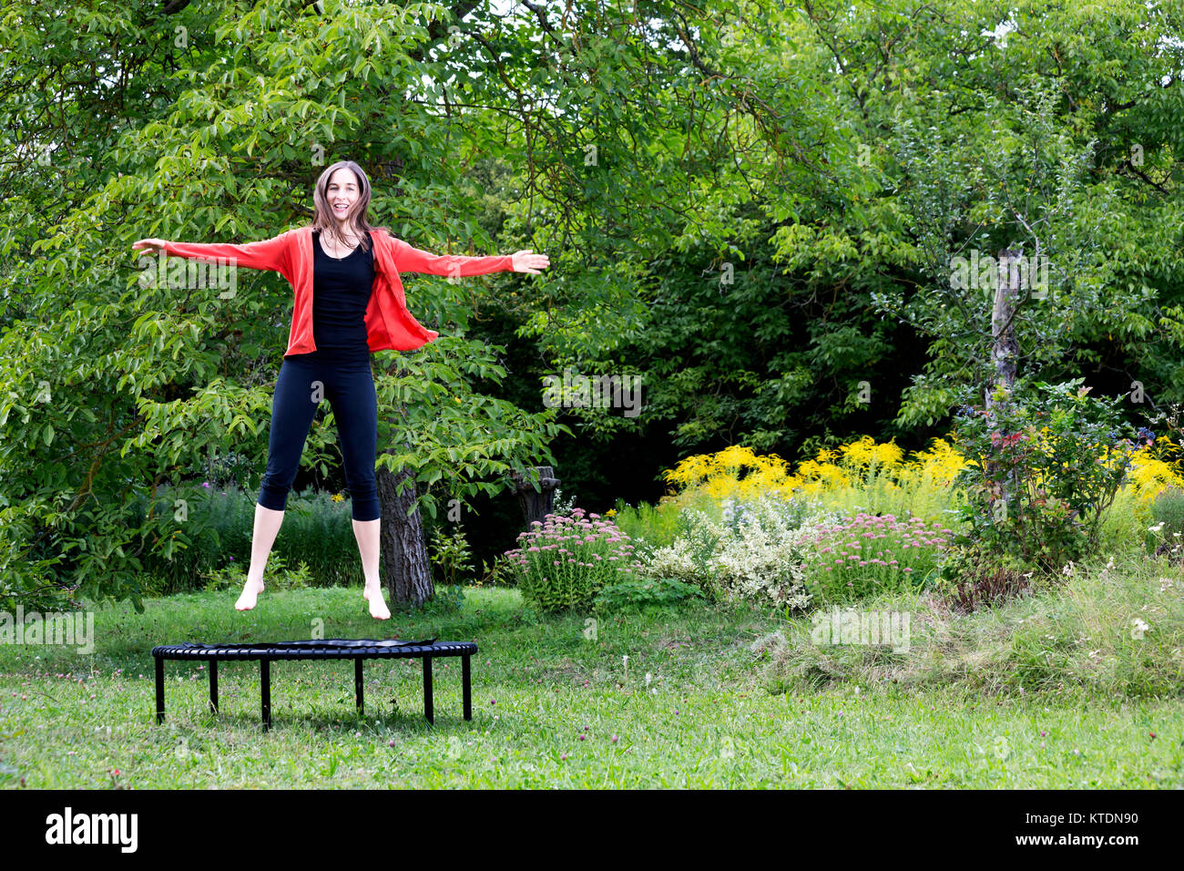 Laughing woman jumping on trampoline in the garden Stock Photo - Alamy
