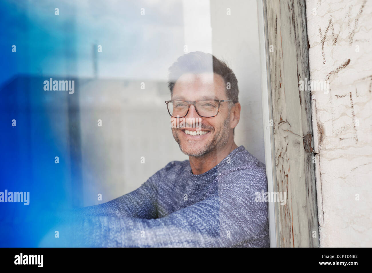 Portrait of laughing man behind glass pane wearing glasses Stock Photo ...