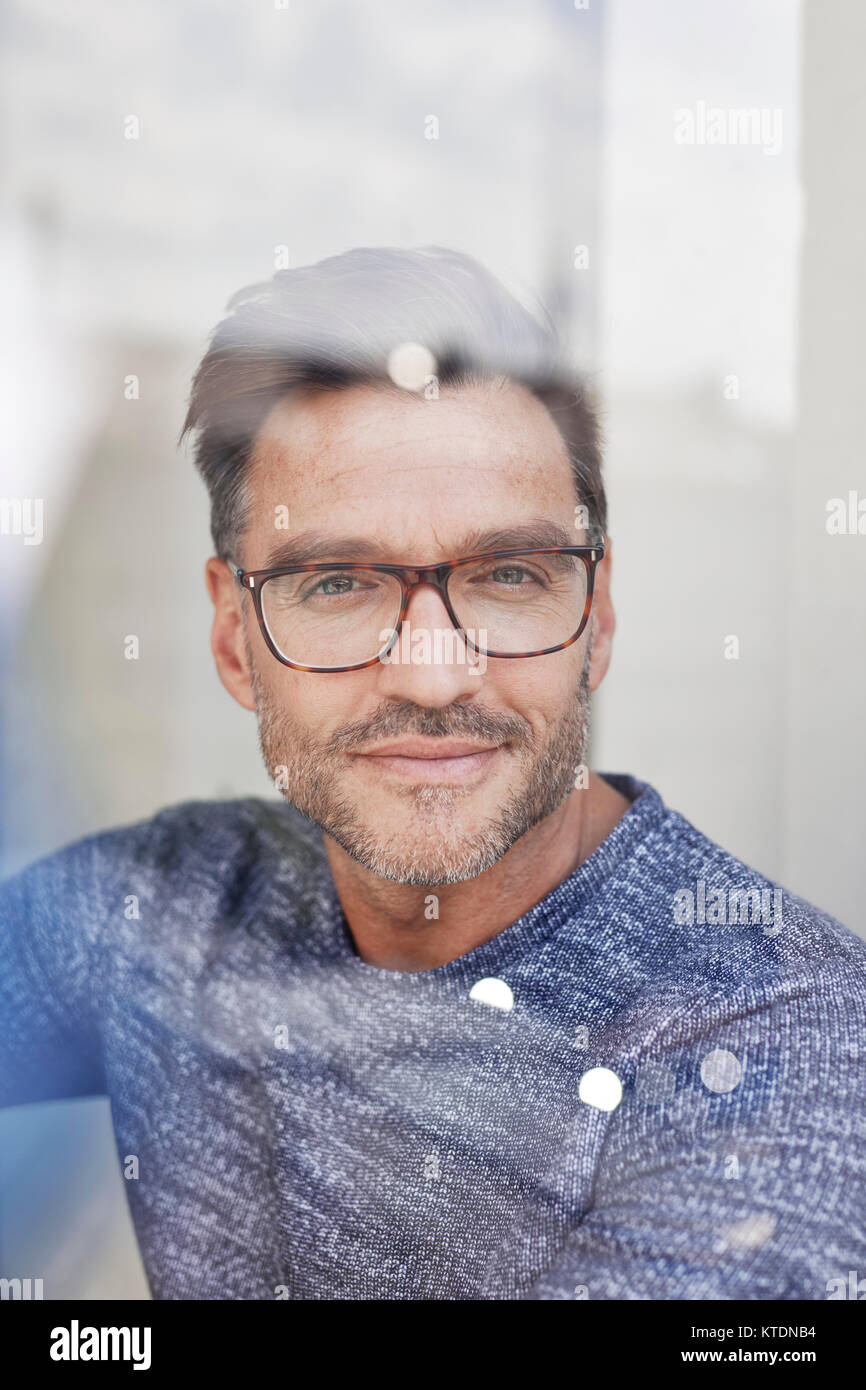Portrait of smiling man behind glass pane wearing glasses Stock Photo ...