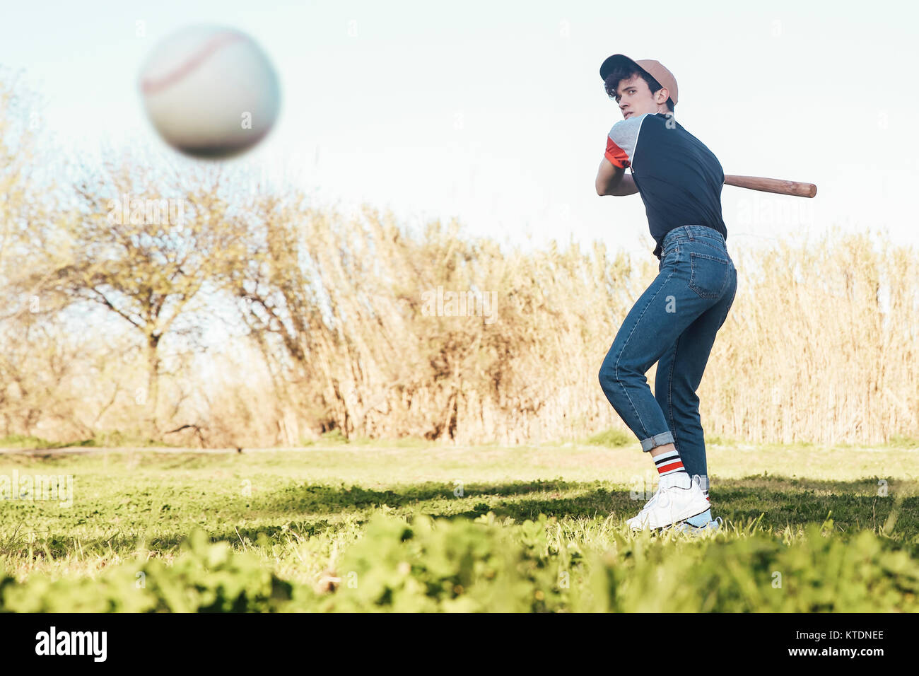 Young man batting a baseball in park Stock Photo - Alamy