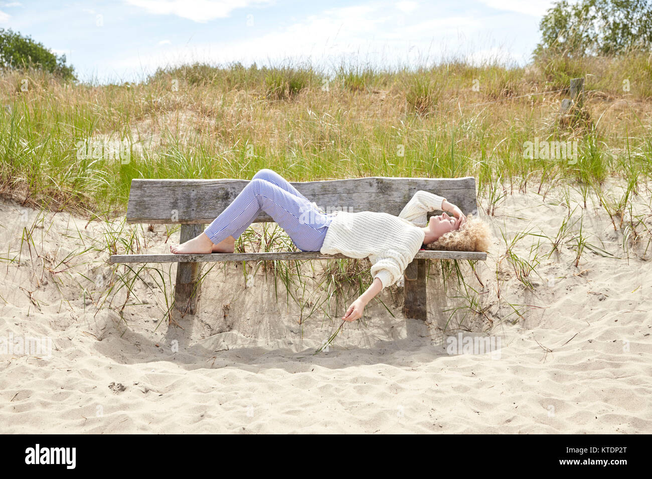 Young woman relaxing on bench in beach dunes Stock Photo - Alamy