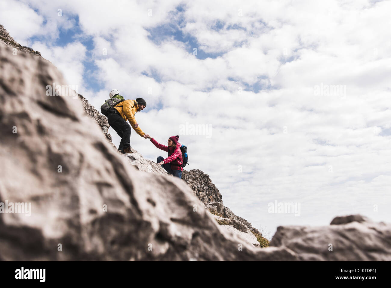 Germany, Bavaria, Oberstdorf, man helping woman climbing up rock Stock ...