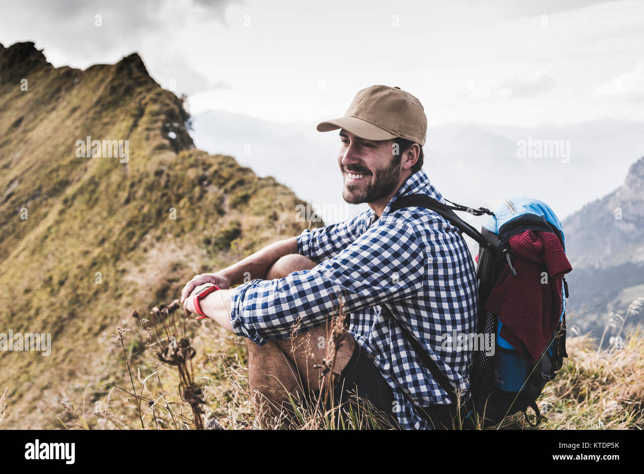 Germany, Bavaria, Oberstdorf, smiling hiker resting on mountain ridge ...