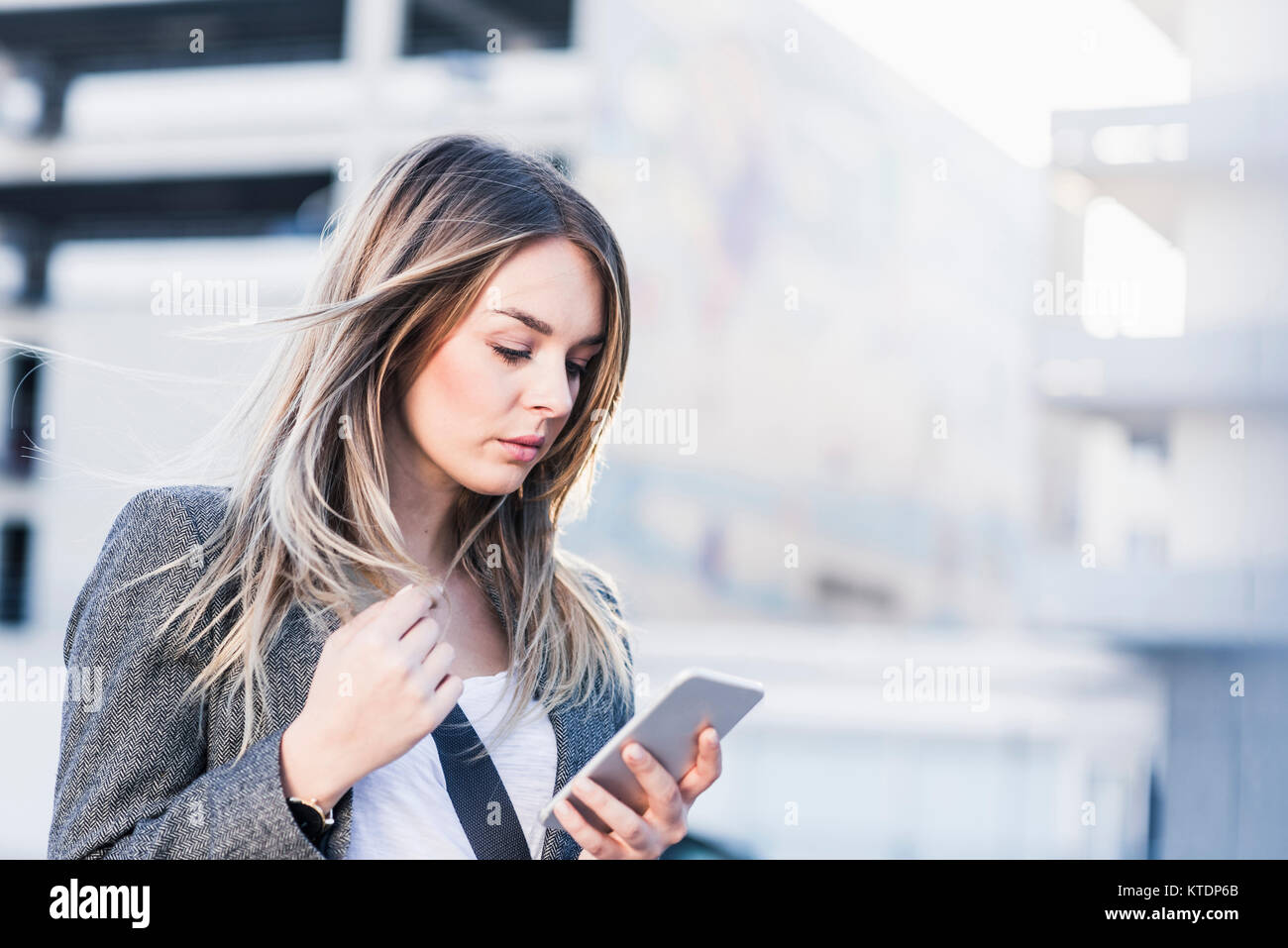 Serious young woman checking cell phone outdoors Stock Photo - Alamy