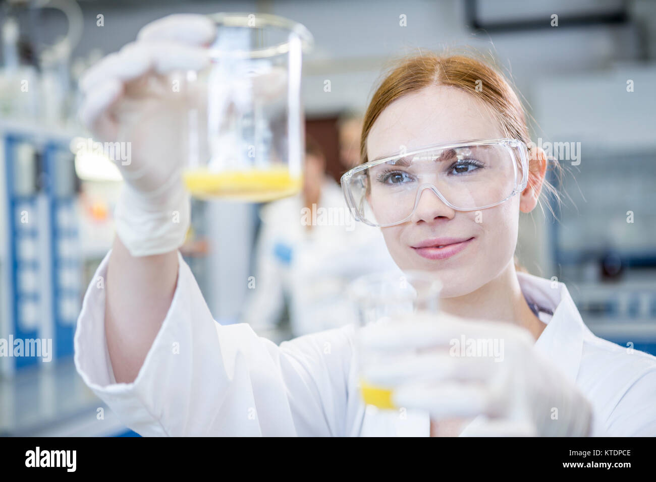 Scientist in lab holding up two beakers with liquid Stock Photo - Alamy