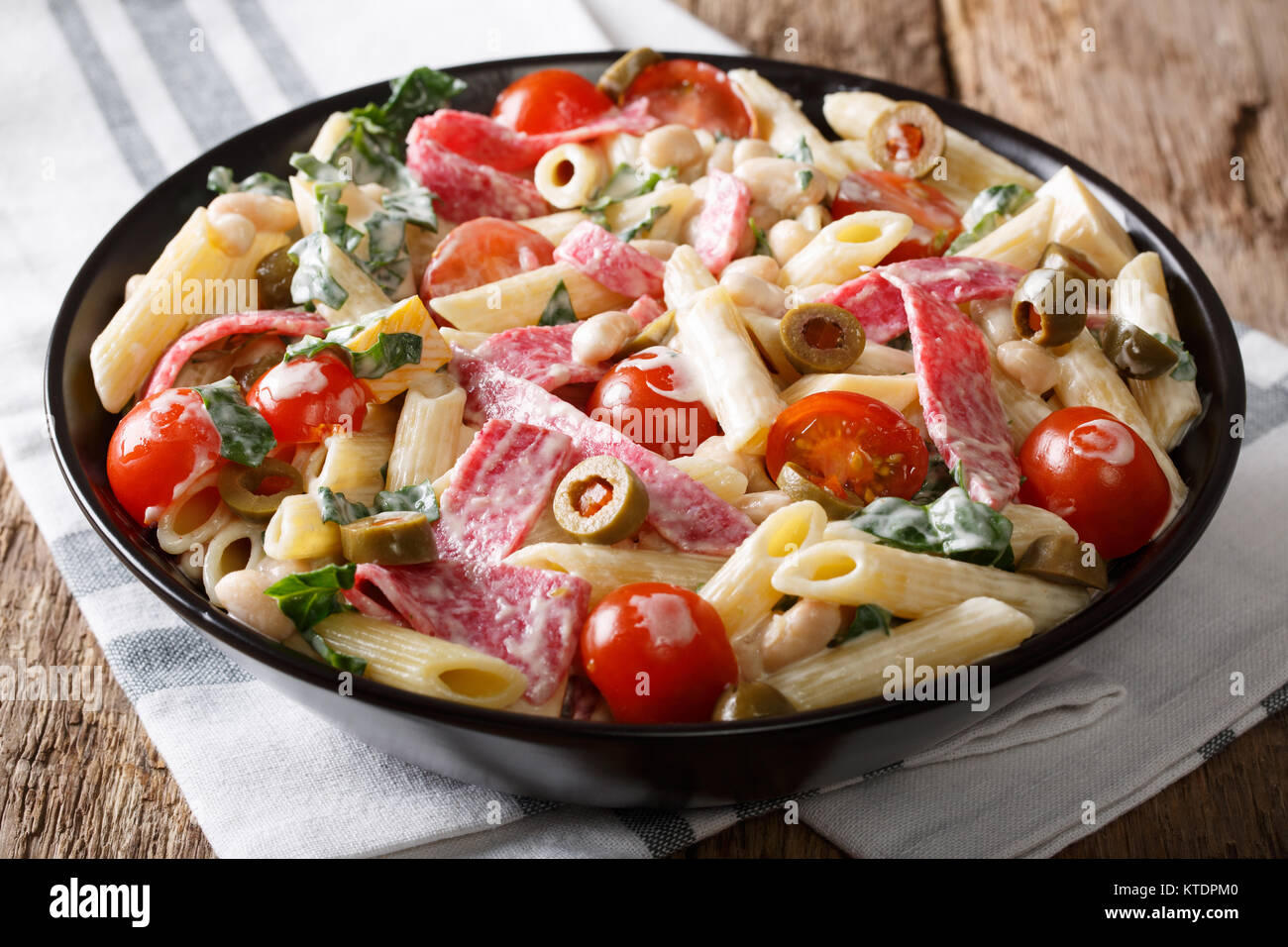 Italian penne pasta with sausage, cheese, and vegetables close-up on a ...