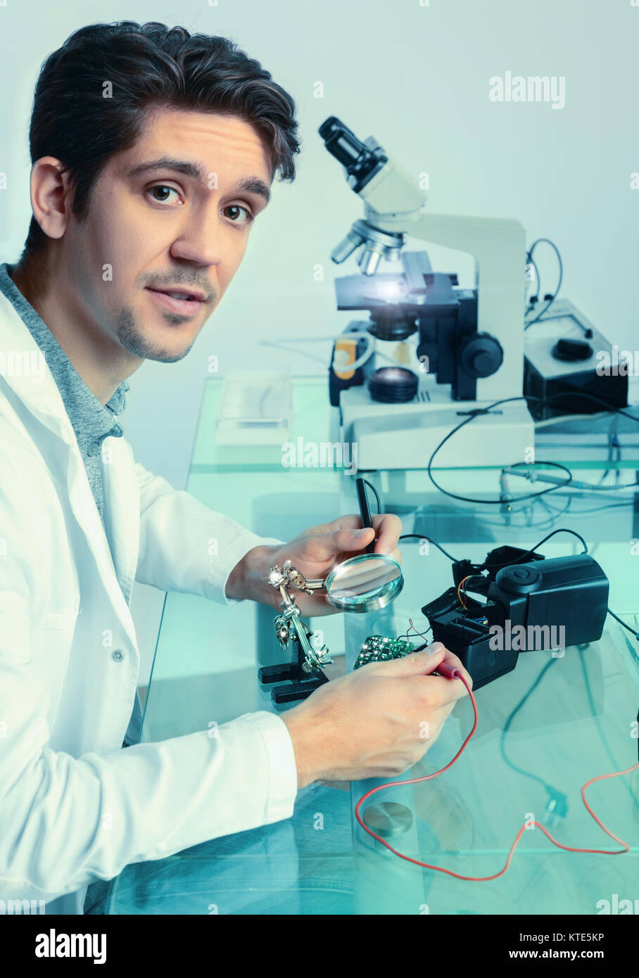 Young energetic male tech fixes electronic device, shallow DOF, focus ...