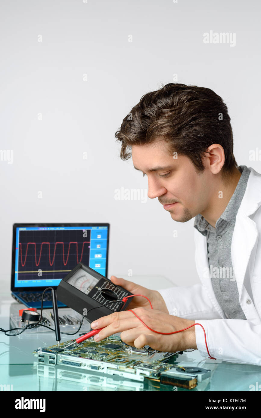 Young energetic male tech or engineer repairs electronic equipment ...