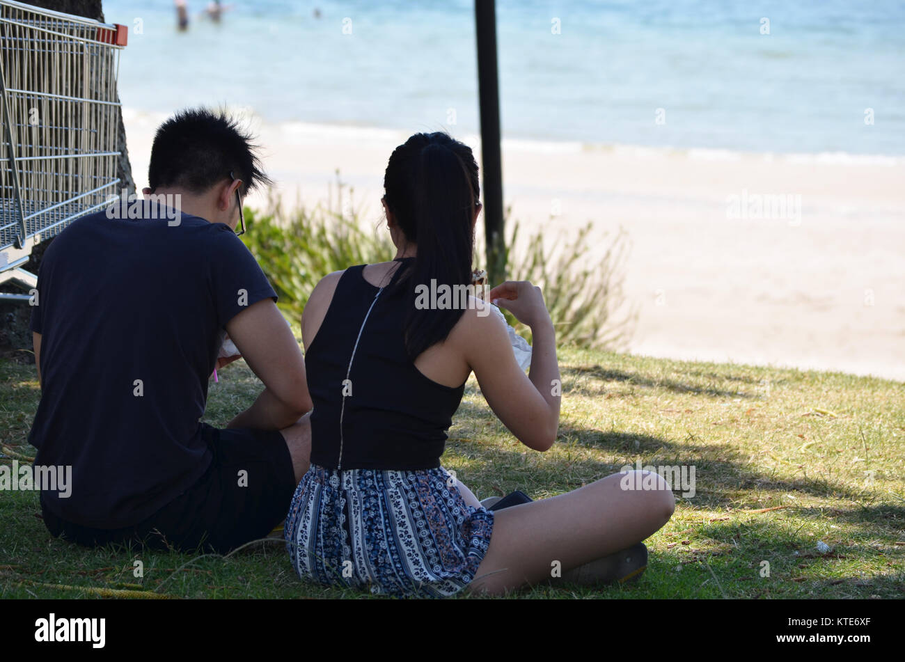Young Asian couple sitting together talking Stock Photo - Alamy