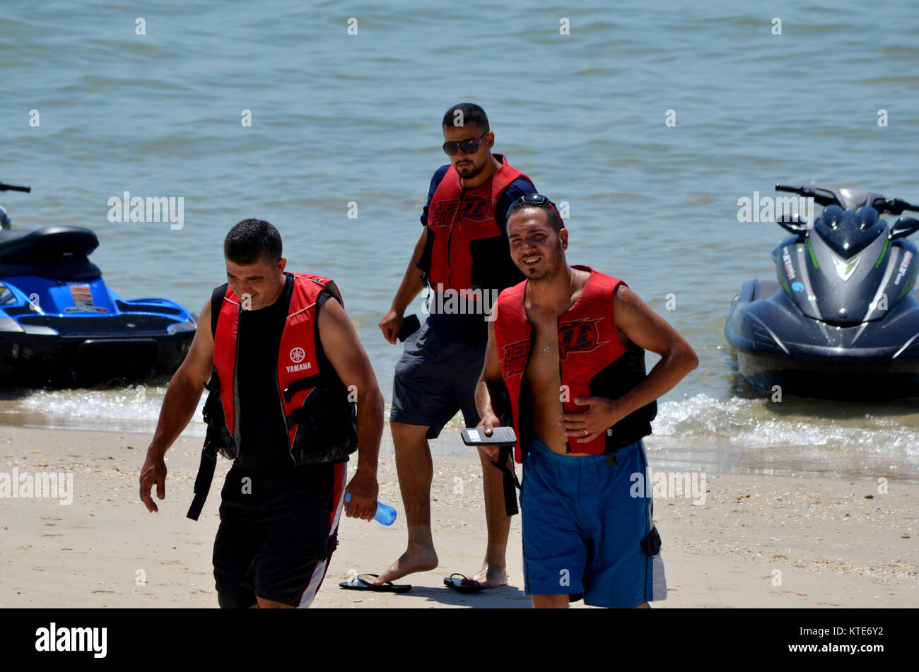 Men on beach with jet skis in background Stock Photo - Alamy