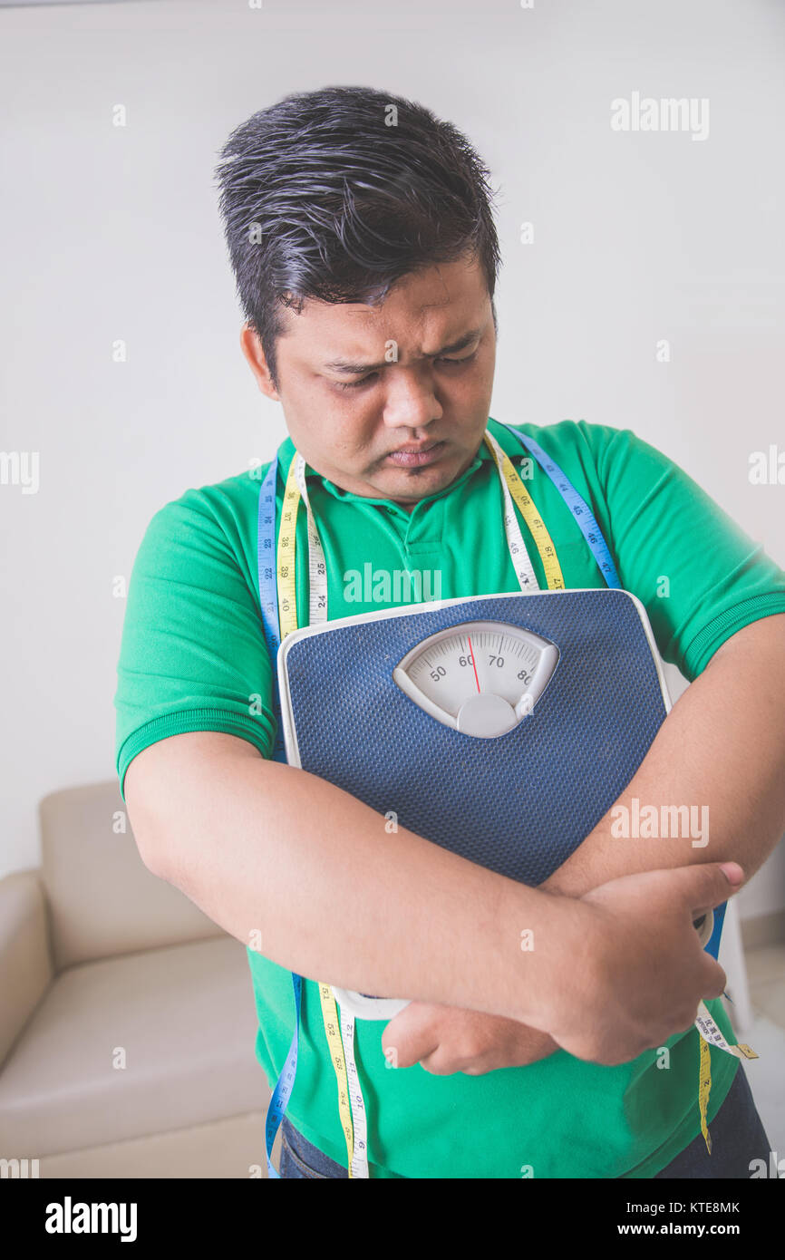sad obese man holding a weight scale, thinking about his weight Stock ...
