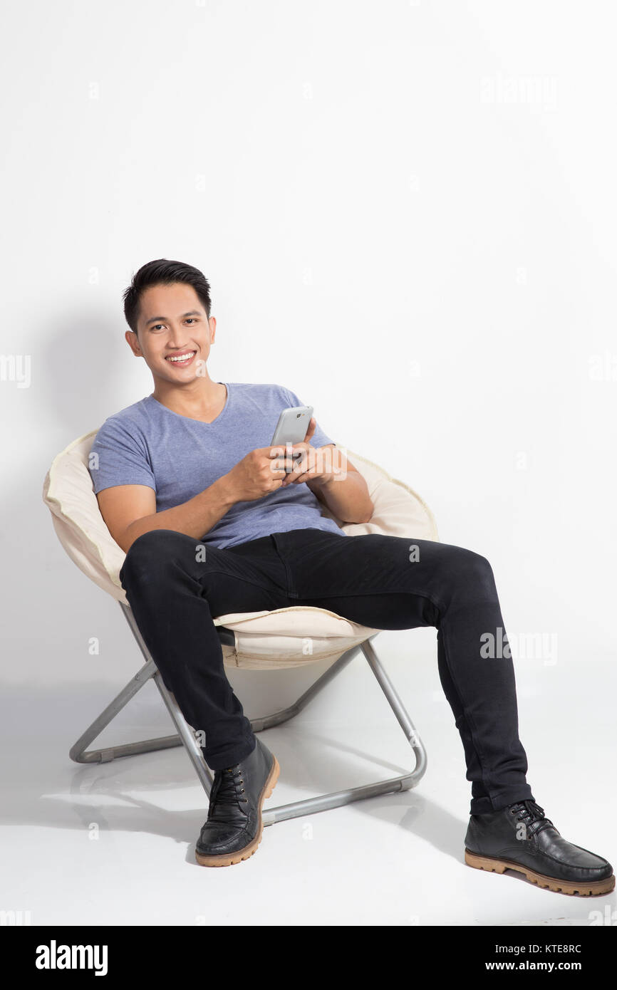 man holding a handphone while sitting on the chair Stock Photo - Alamy