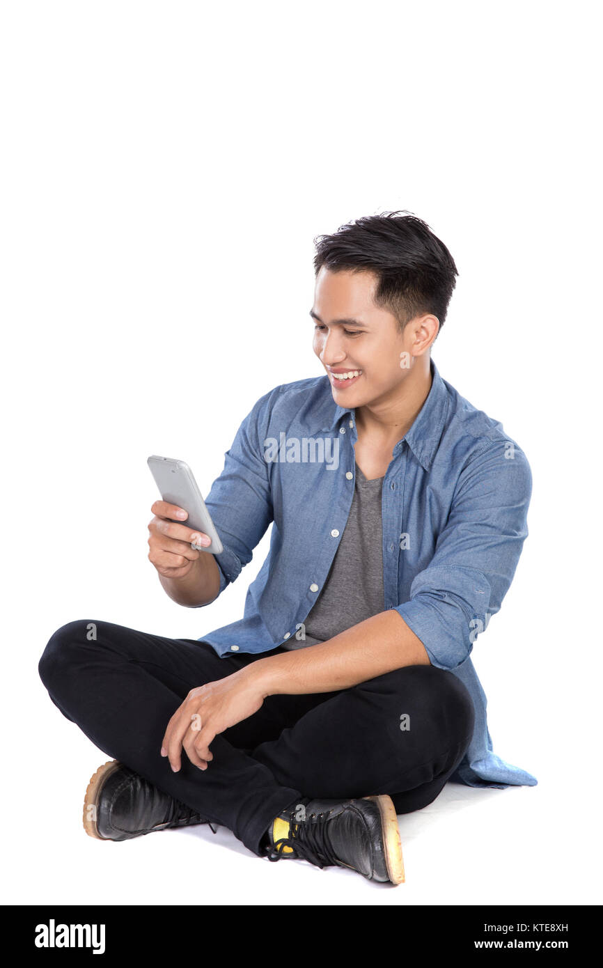 Young asian man look at the handphone while sitting on the floor Stock ...