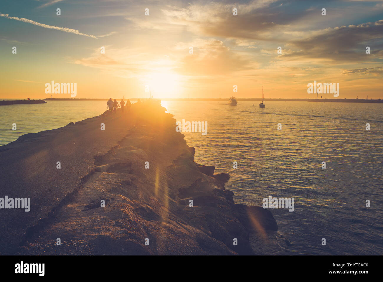 Boats sailing into Marina Del Rey and people walking along the jetty ...