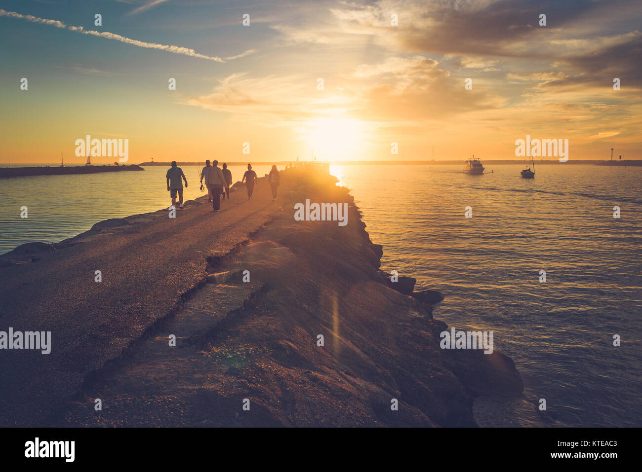 Boats sailing into Marina Del Rey and people walking along the jetty ...