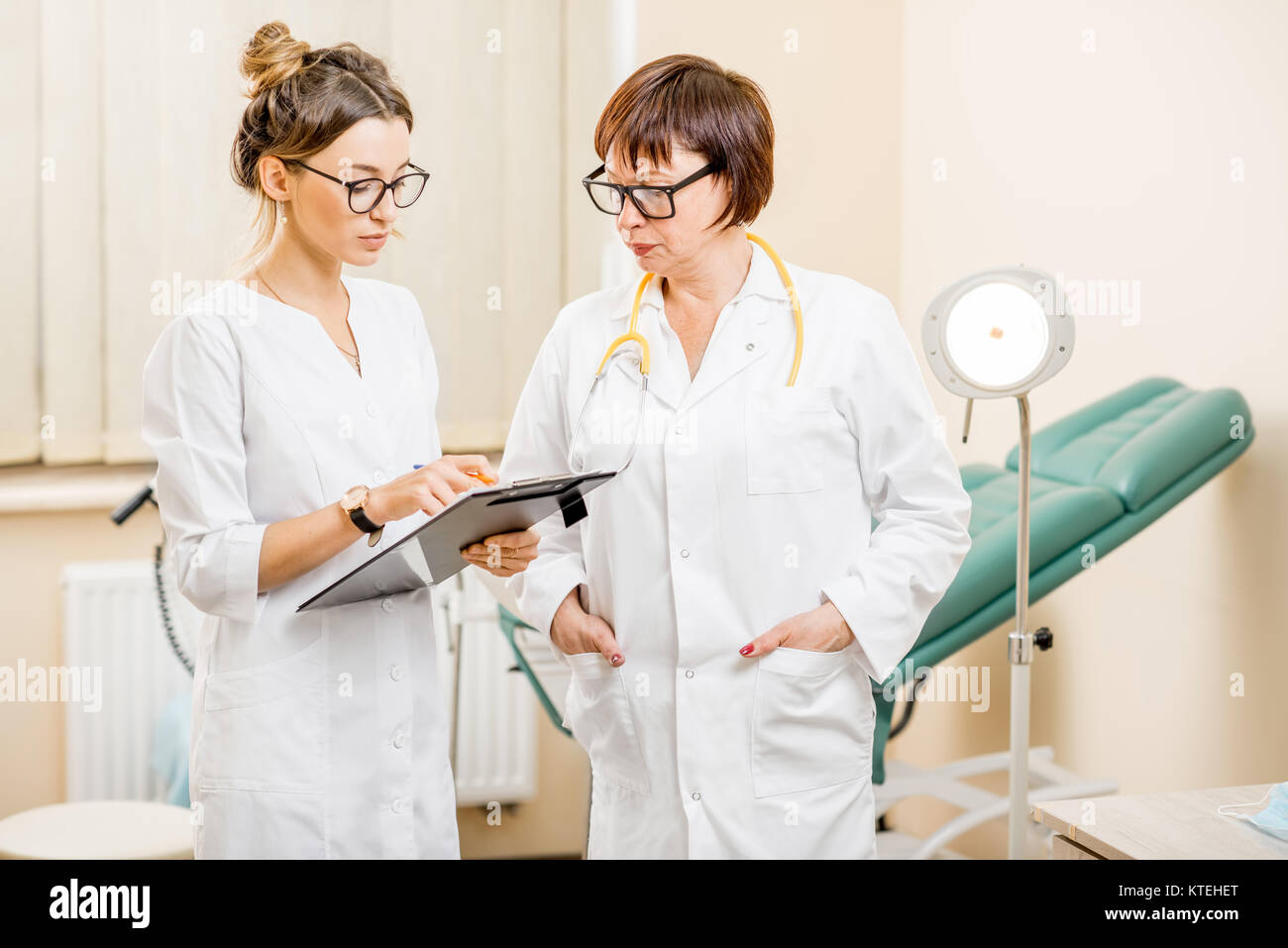 Senior doctor talking with young woman assistant standing in the ...
