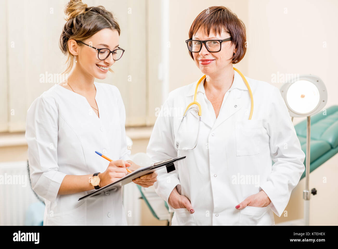 Senior doctor talking with young woman assistant standing in the ...