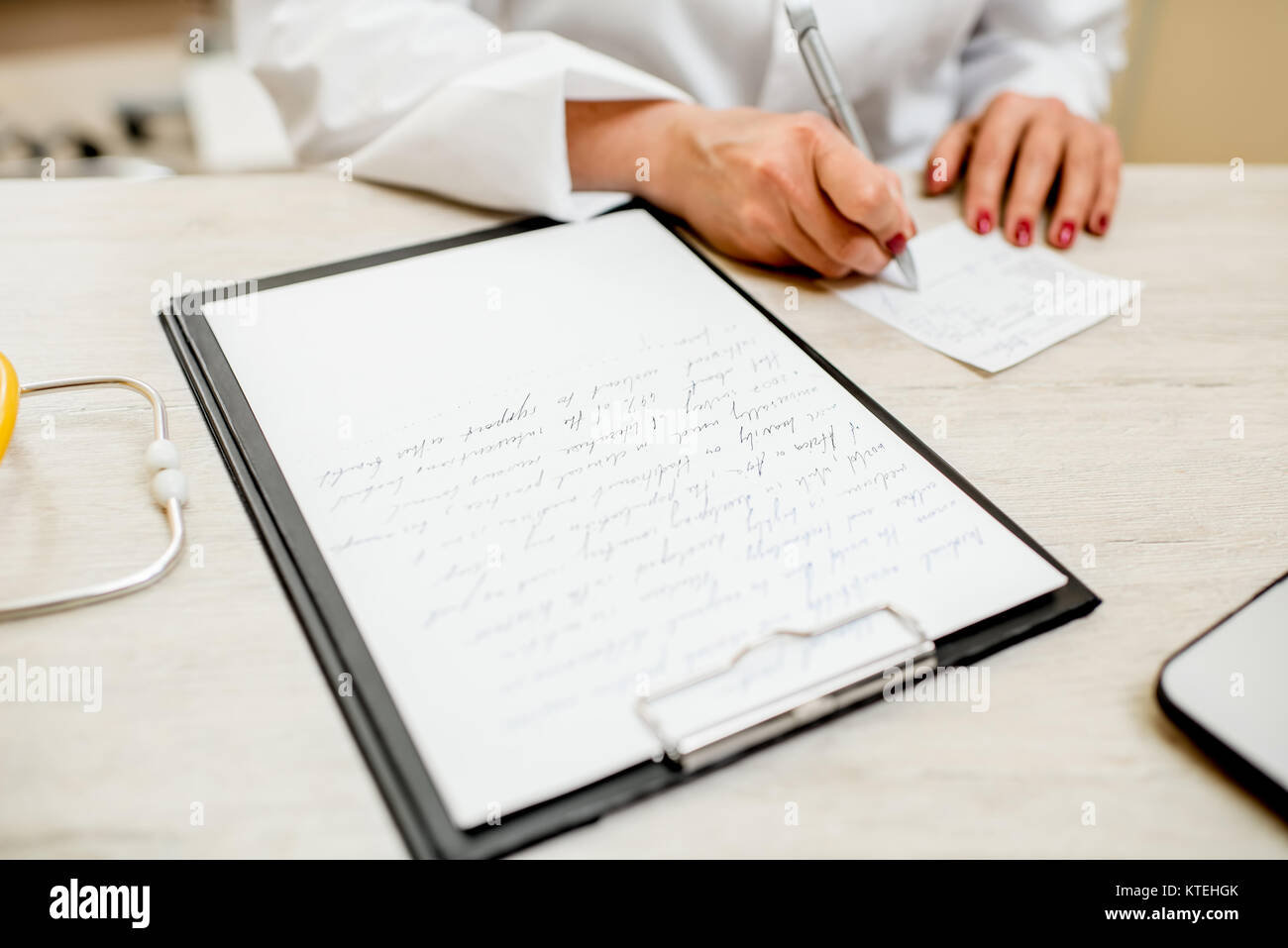 Senior doctor writing recipe on the table with documents. Close-up view ...