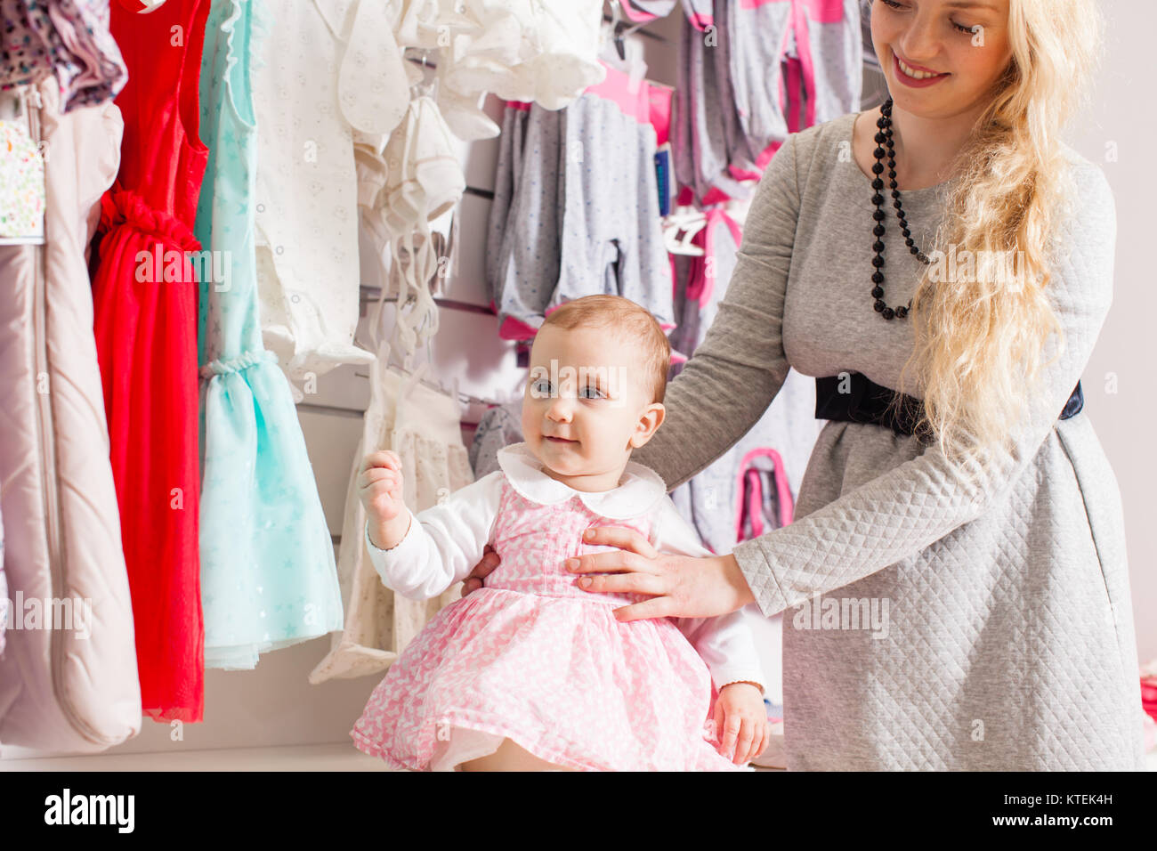 Cute beautiful little girl with her mother buying dress in shop Stock ...