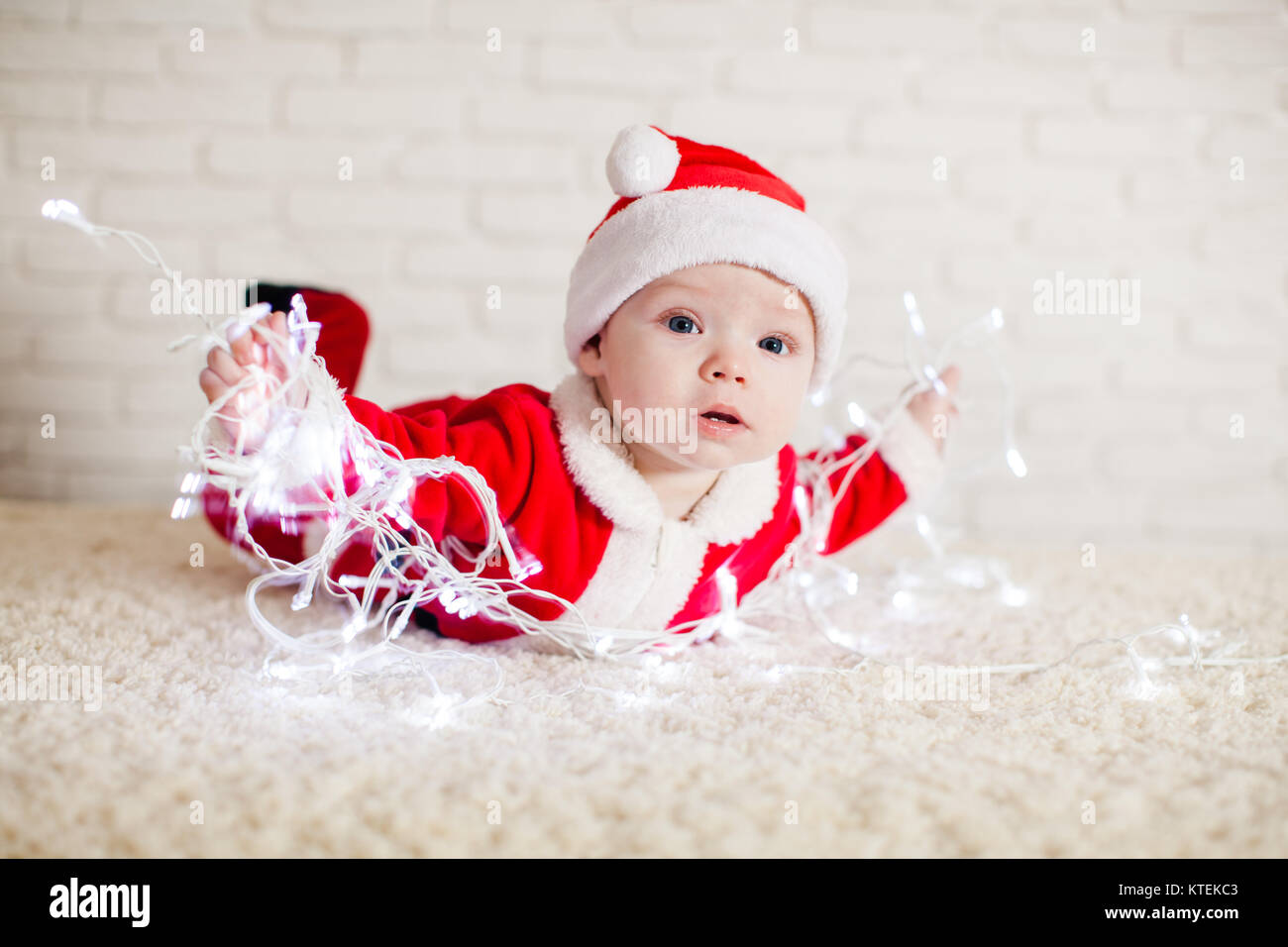 Adorable little Santa baby play with Christmas lights Stock Photo - Alamy