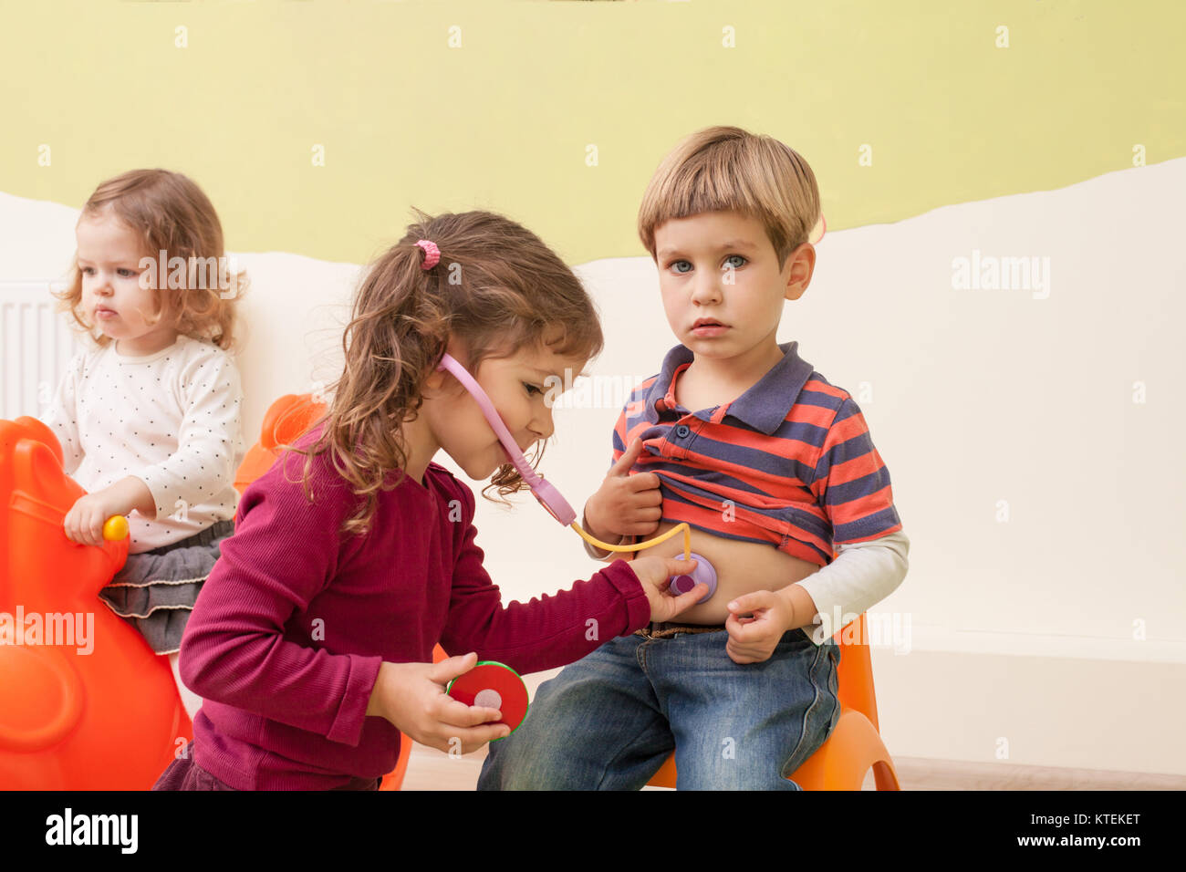 Girl with stethoscope is playing in a doctor and listening the boy's ...