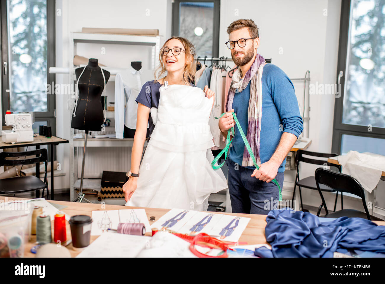 Young woman client fitting wedding dress with man tailor standing at ...