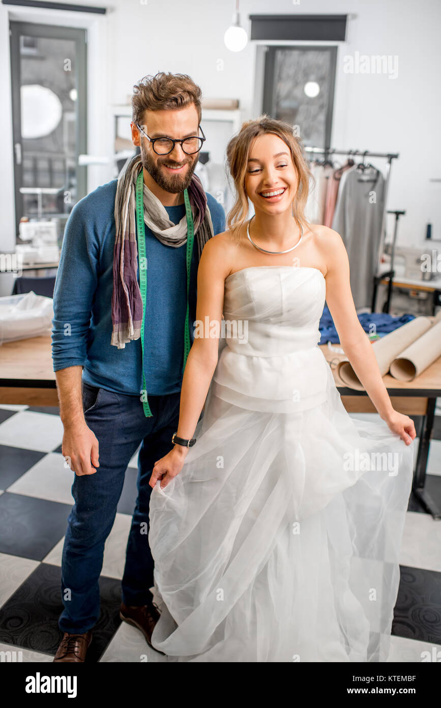 Young woman client fitting wedding dress with man tailor standing at ...