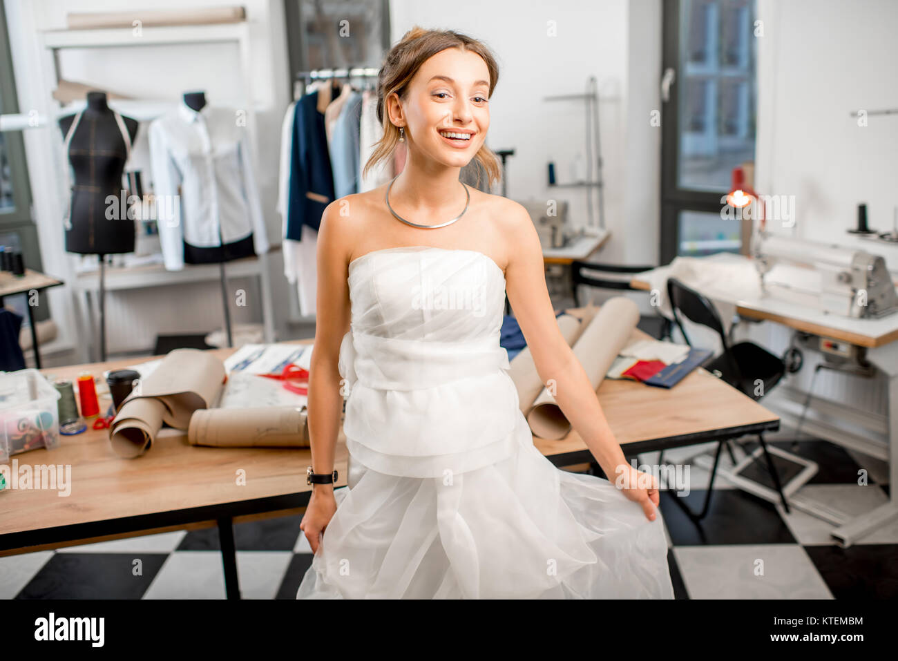 Young woman client fitting wedding dress standing at the tailor studio ...