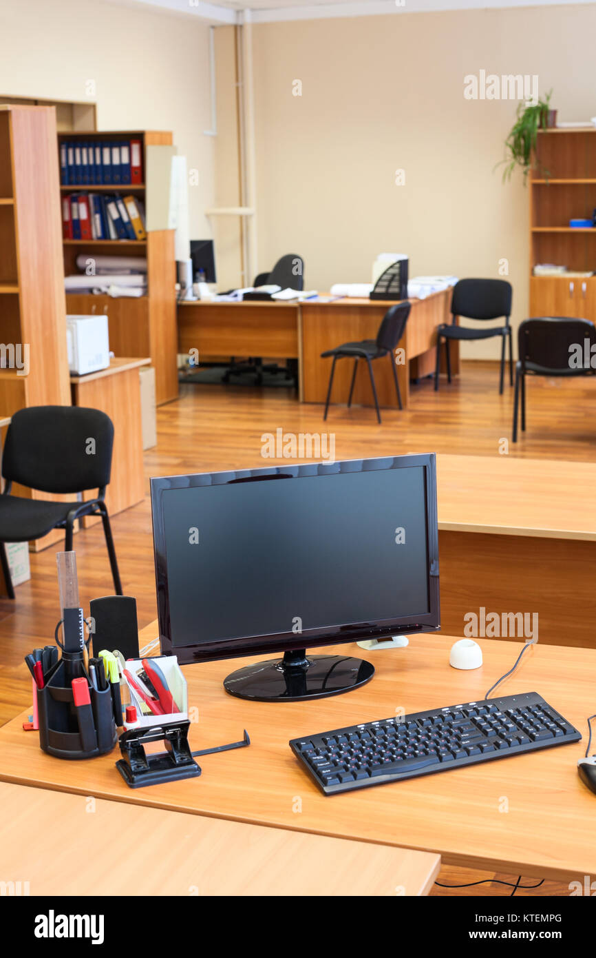 Black lcd computer monitor is off in empty office room after end of the ...