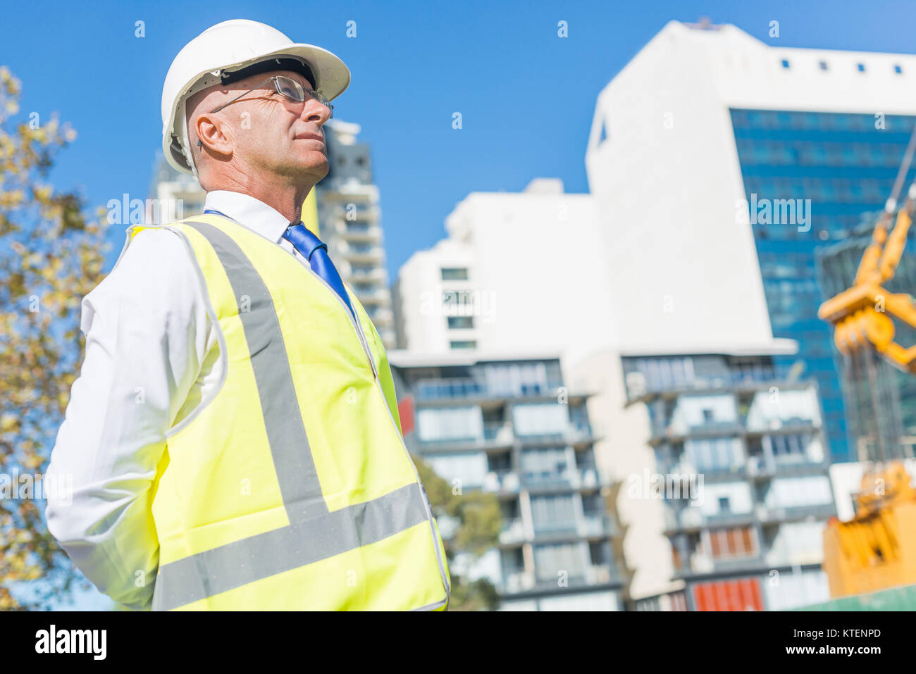 Senior foreman in glasses doing his job at building area on sunny day ...