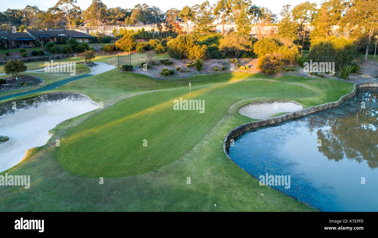 Aerial view of golf course green with flag, bunkers and dam water ...
