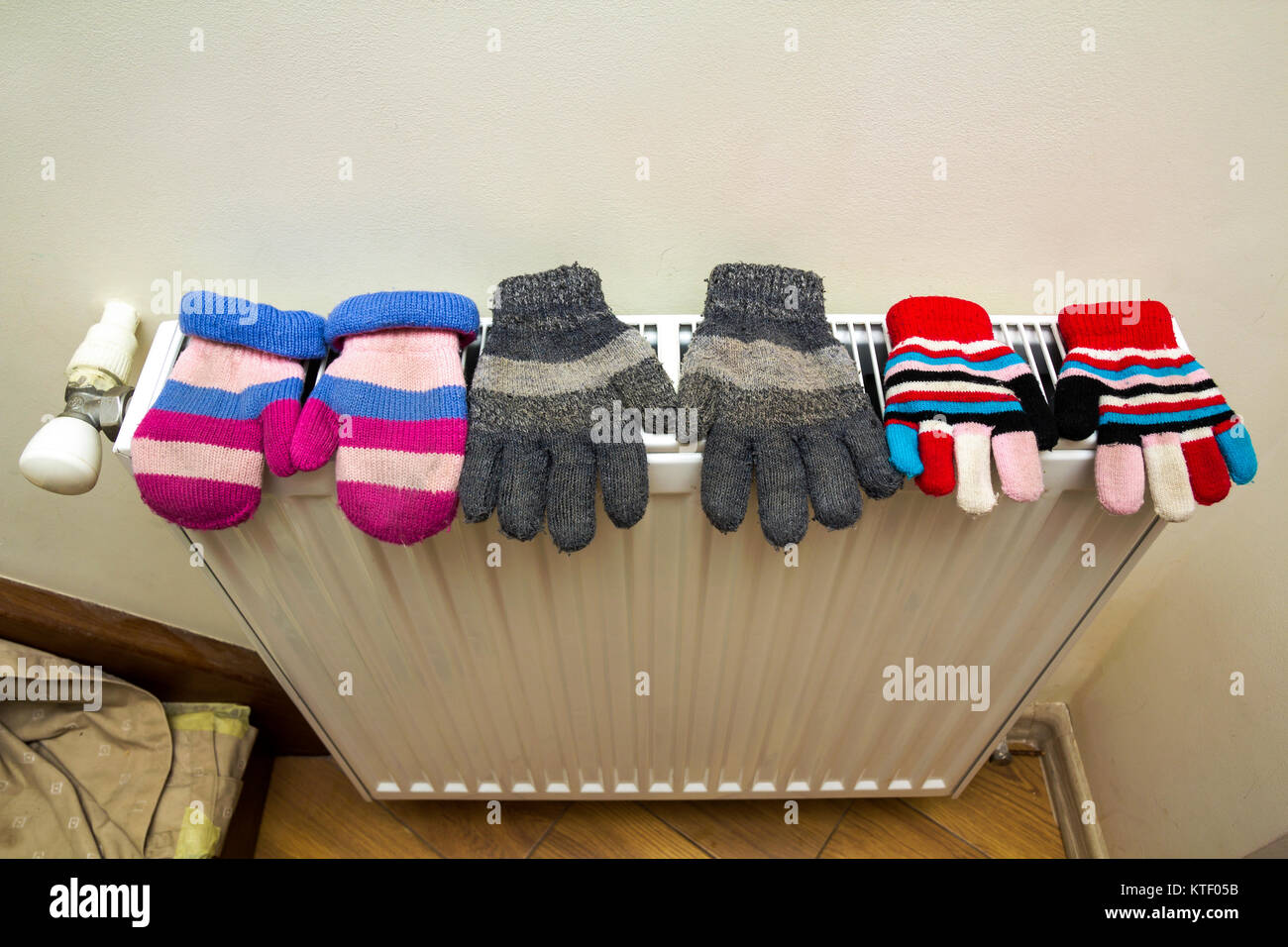 Children's warm hand knitted striped woolen gloves drying on heating ...