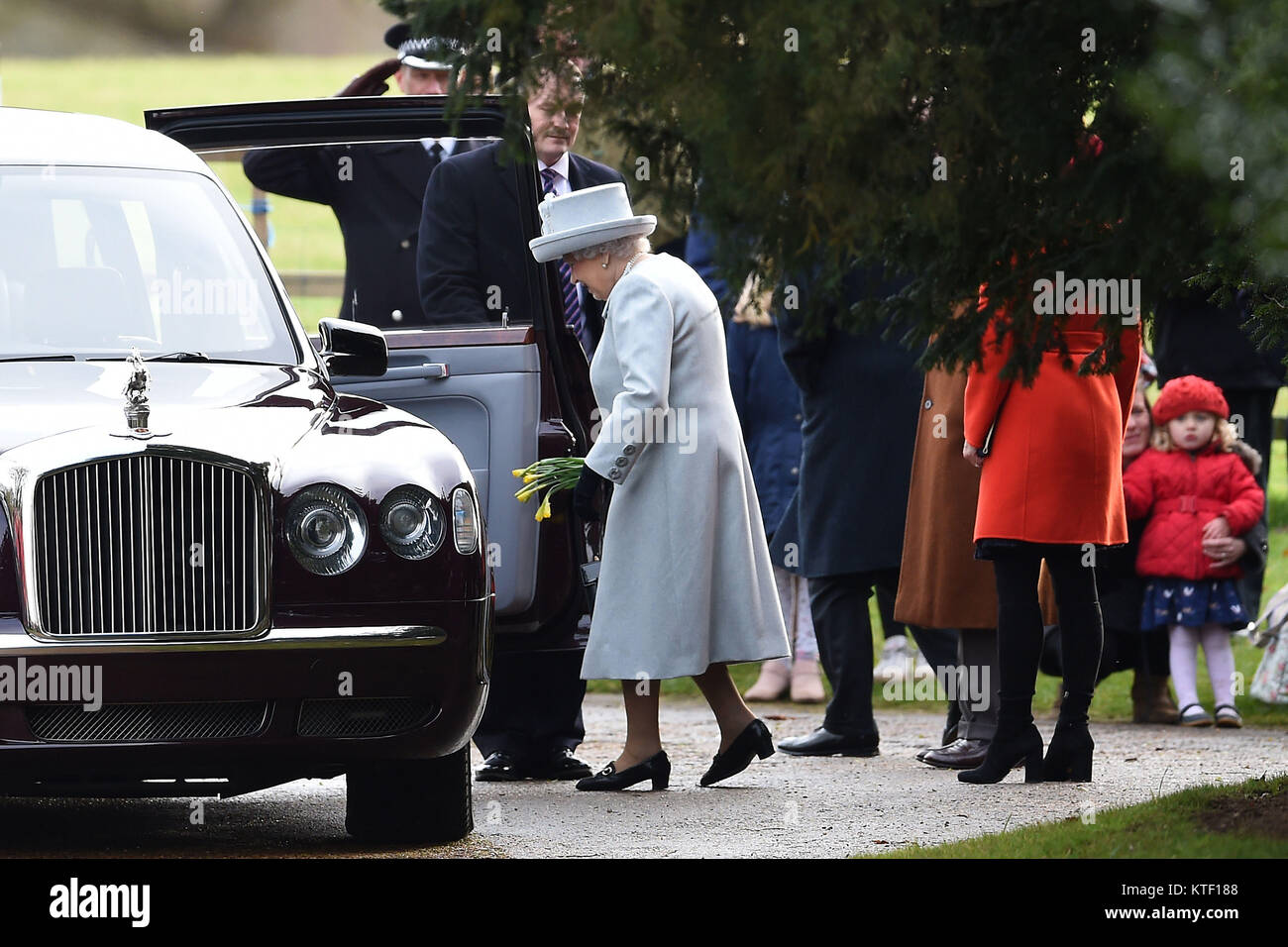 Queen Elizabeth II carries daffodils given by a girl (right) after ...