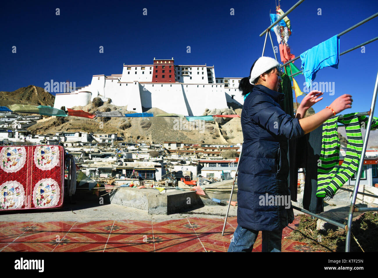 Tibetan woman doing laundry at a flat roof with the Samdruptse Dzong in ...