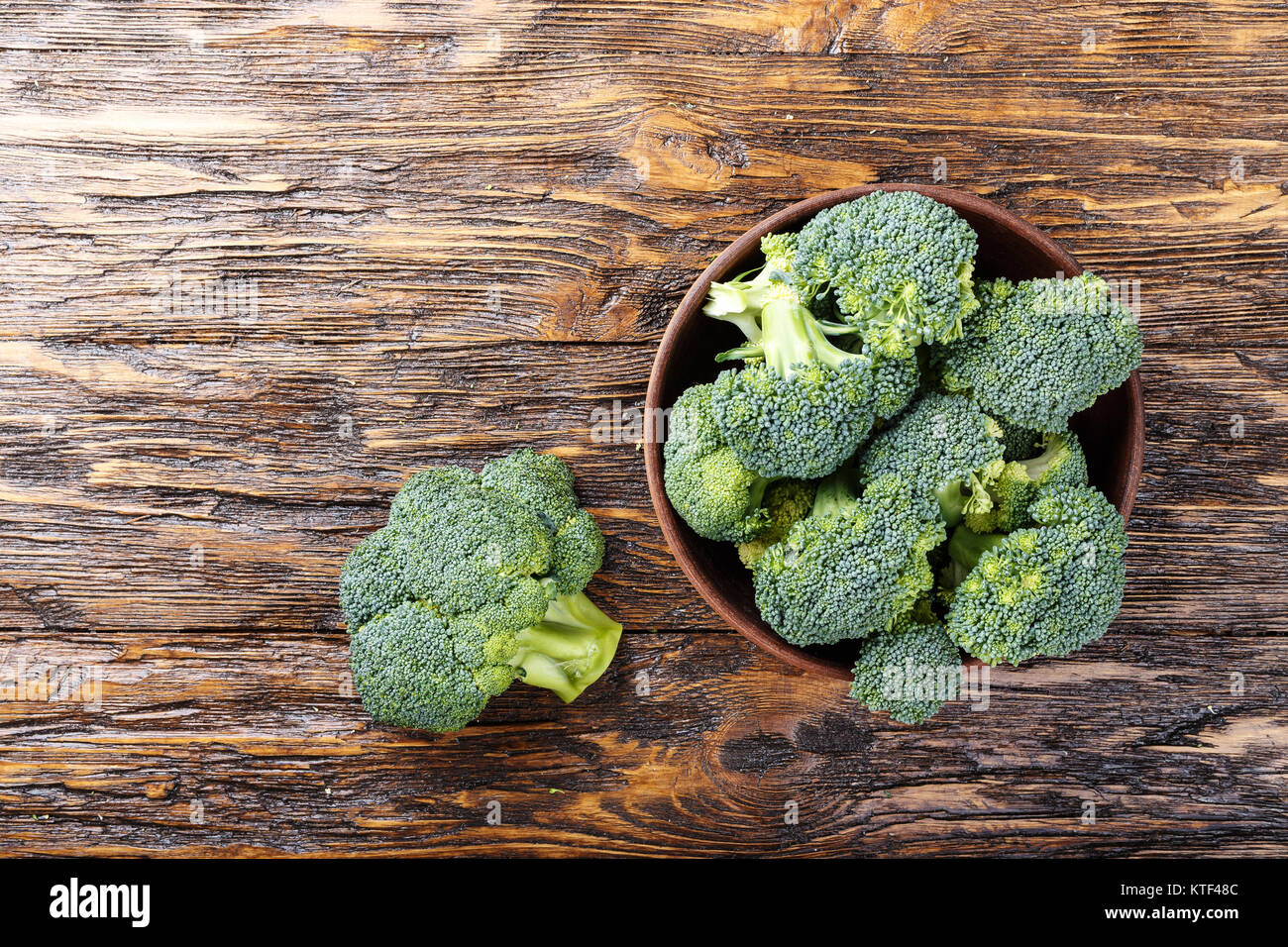 broccoli in a clay plate on a wooden table, next to a whole cabbage are ...