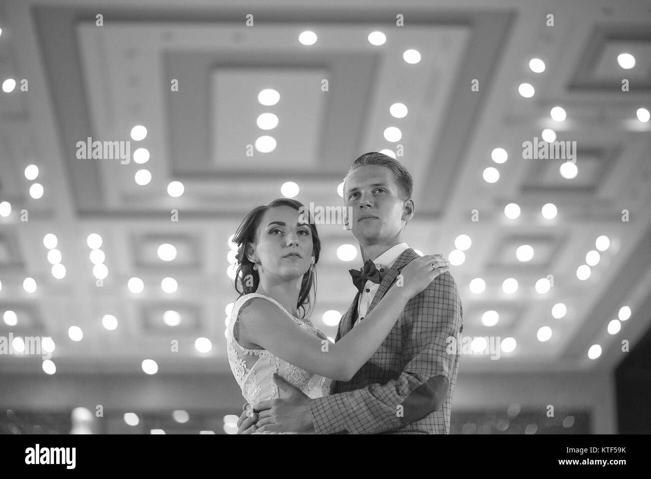 The bride and groom stand on the beautiful porch of the hotel at night ...