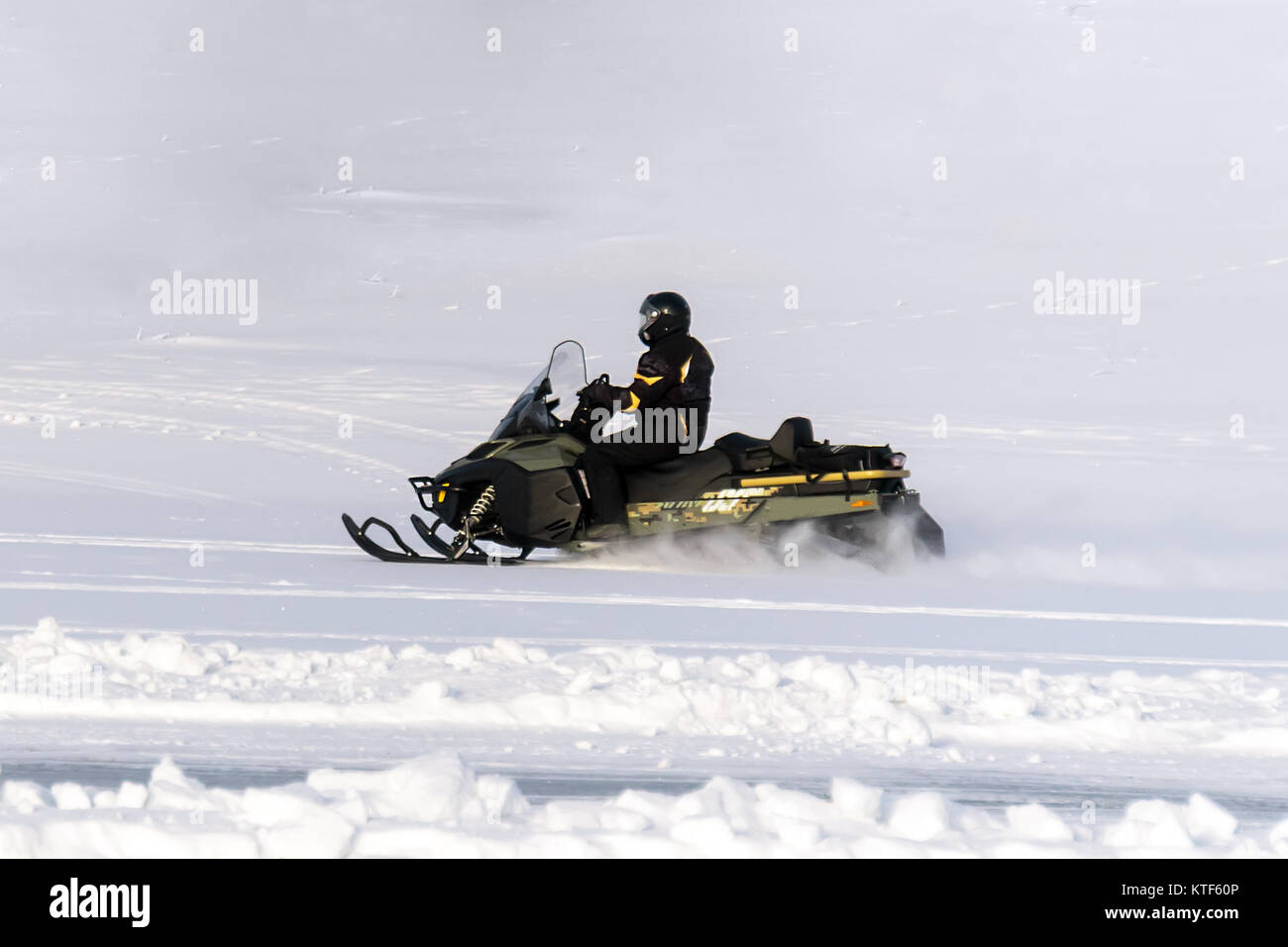 Man driving sports snowmobile in Finnish Lapland in a sunny day ...