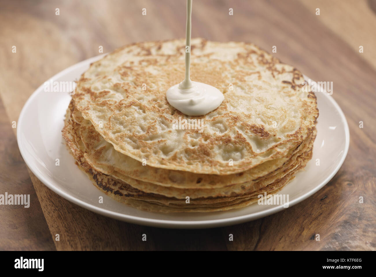 cream pour on freshly made blinis or crepes, simple sweet food Stock ...